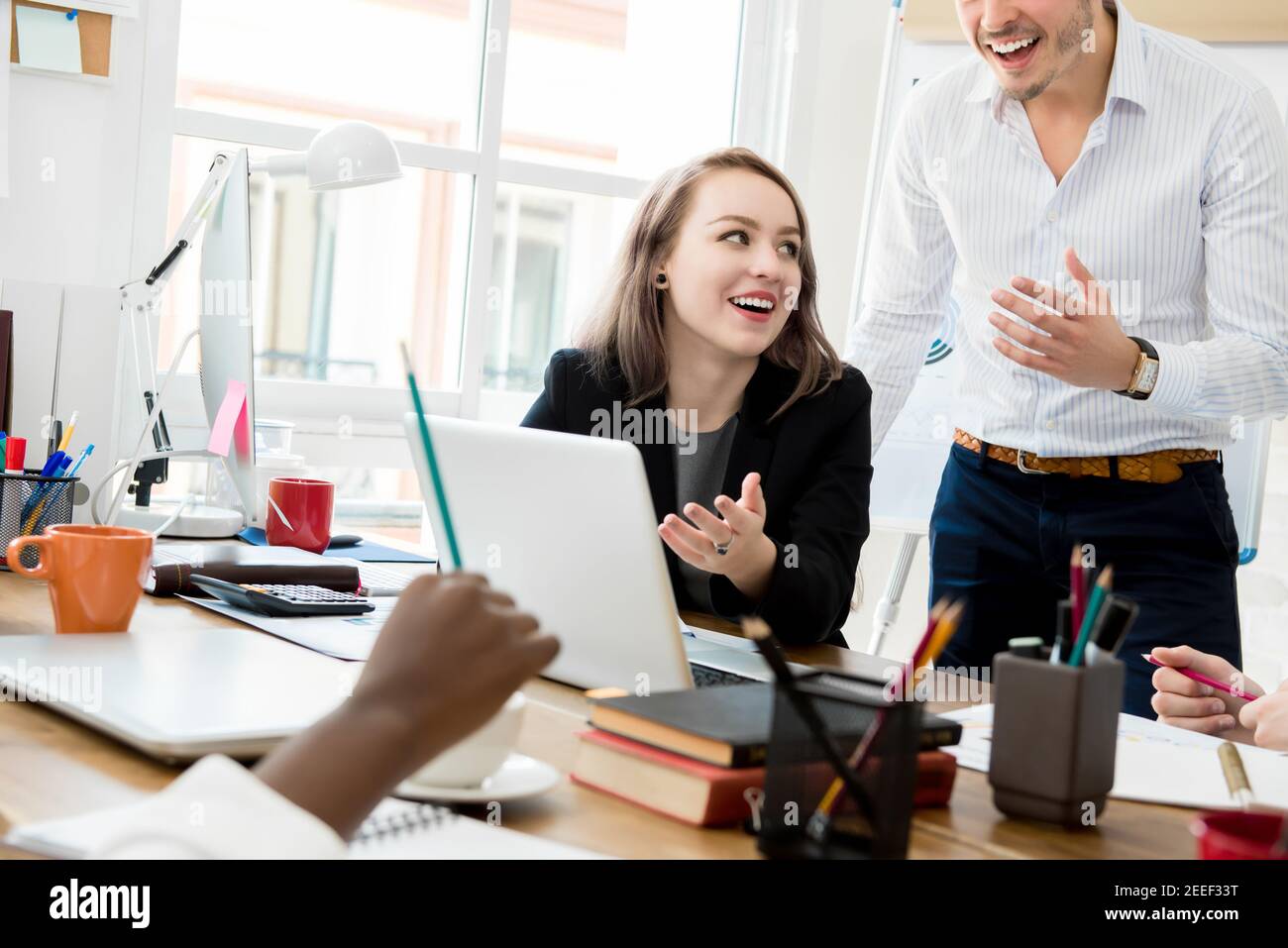 Smiling business colleagues discussing work together in the office ...