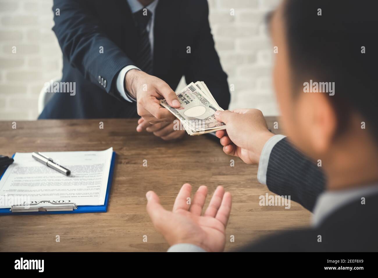 Businessman giving money, Japanese Yen, to his partner while making ...