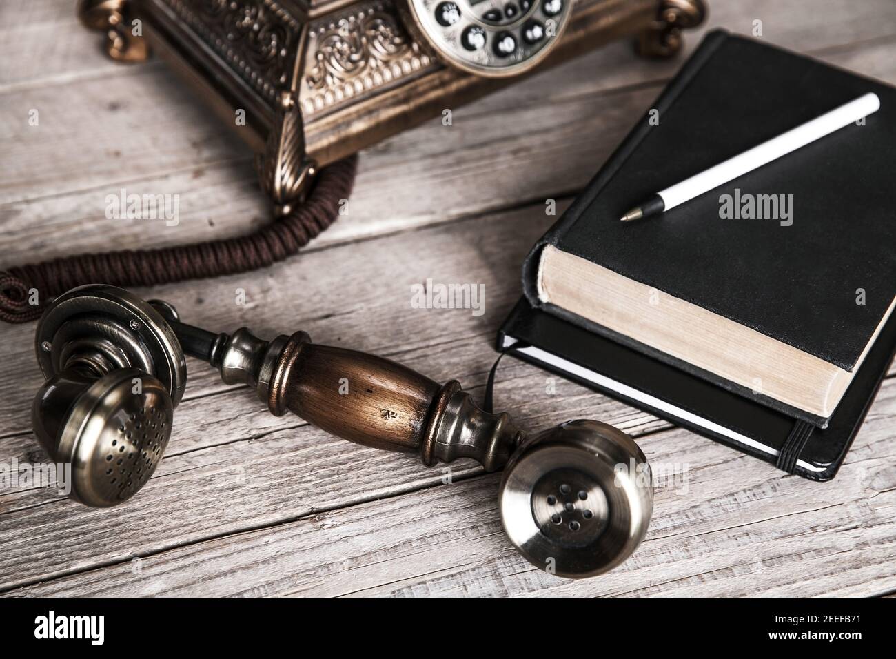 Vintage rotary telephone and old phone book on table near wall and ...