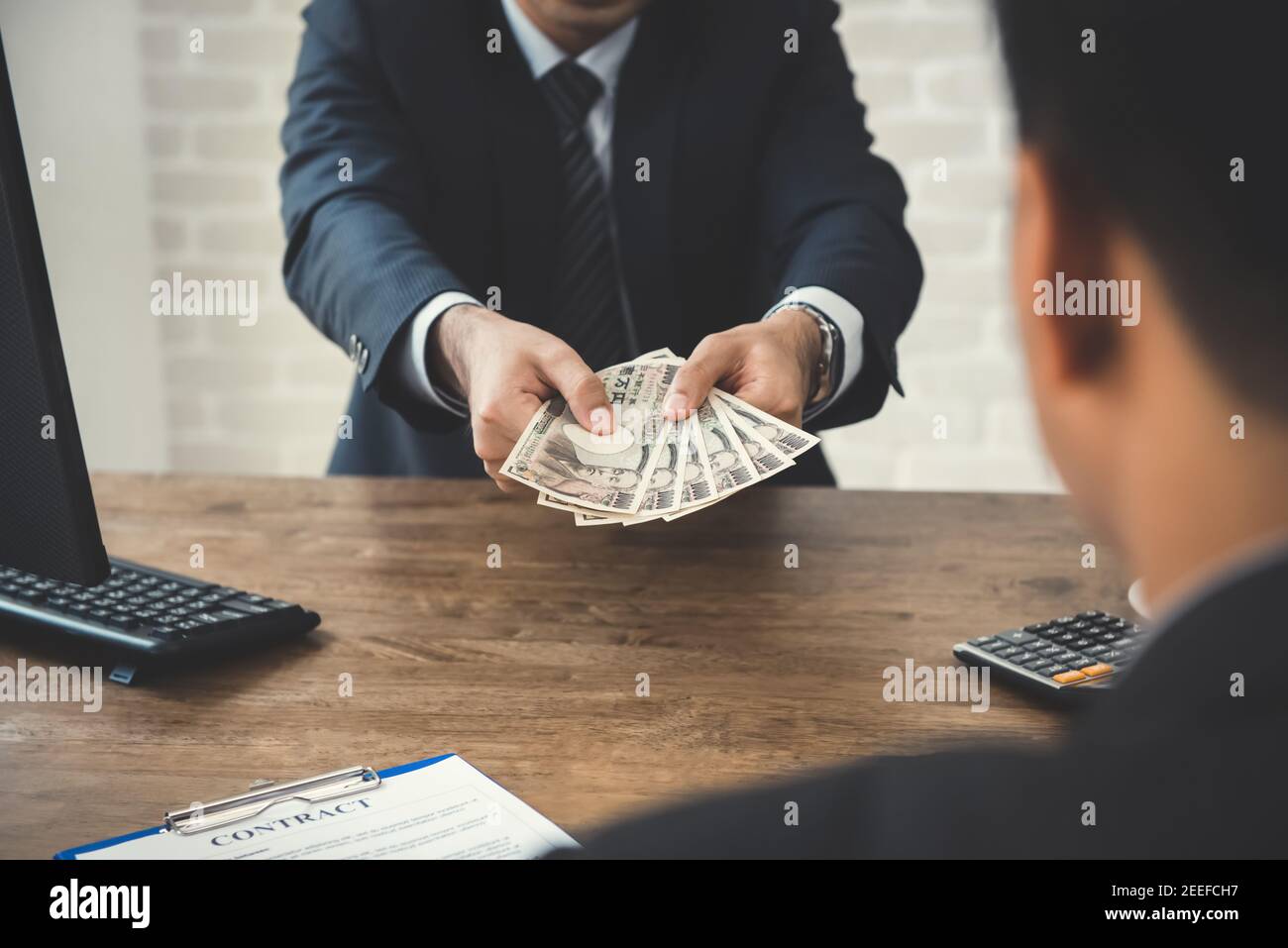 Businessman giving money, Japanese yen banknotes, to his partner while ...