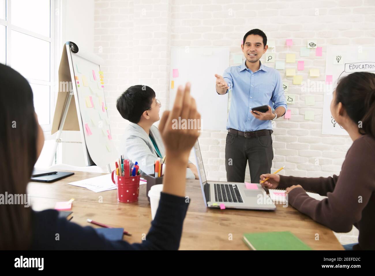 Asian male teacher asking question in the class and one of the student ...