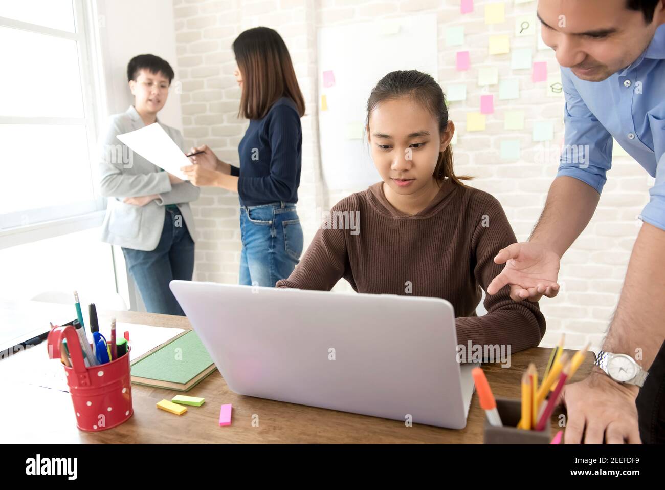 Group of college students and teacher discussing project in classroom ...