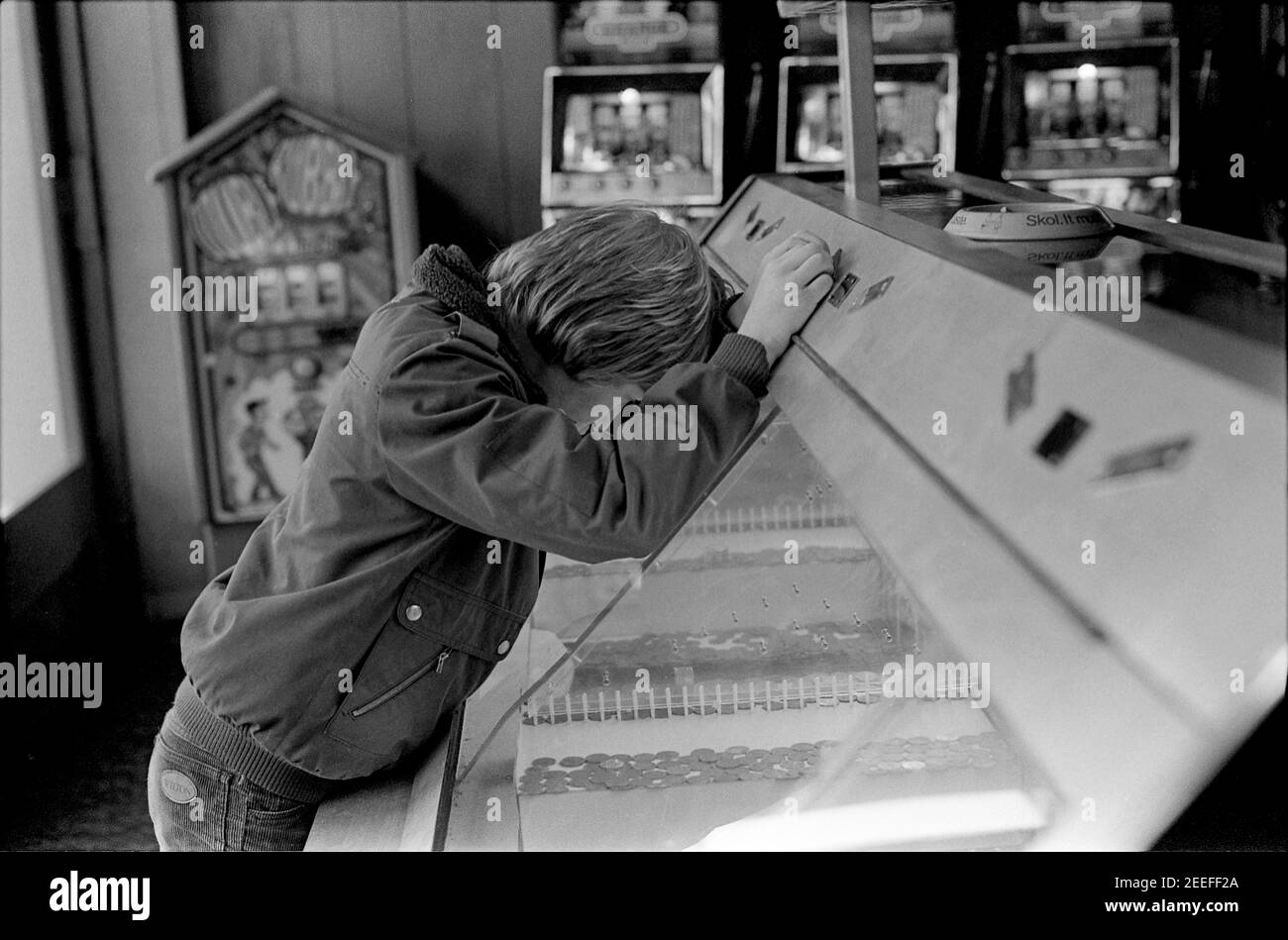 Teenager Leaning on clean sweep, Penny drop Machine Stock Photo - Alamy