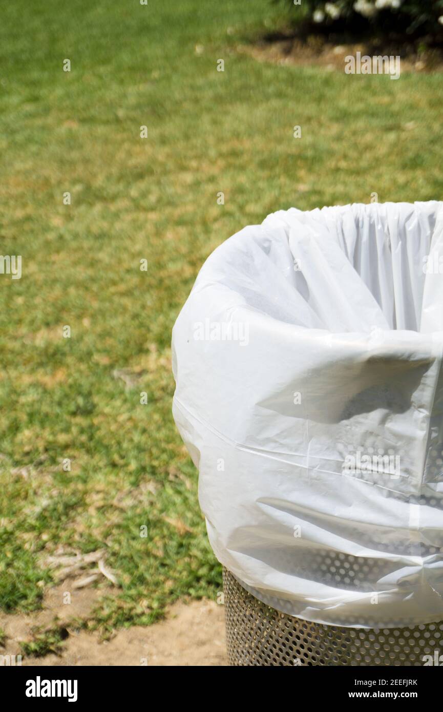 Trash bin in a park with white plastic bag. No people Stock Photo - Alamy