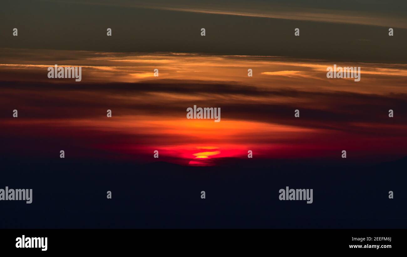 Beautiful sunset with sun disappearing in the dark silhouettes of ...