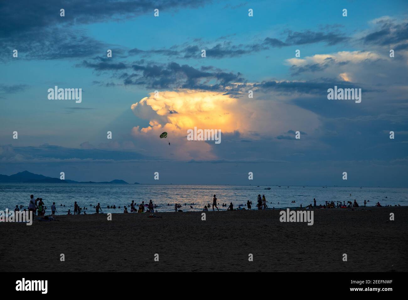 Sunset sea landscape with tourists on beach and bright cloud. Golden ...