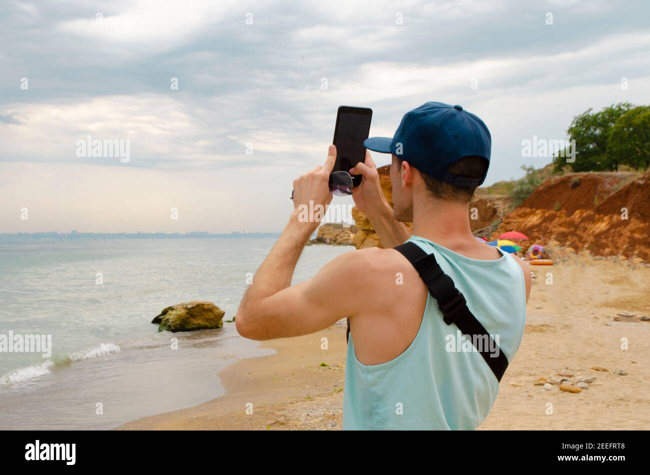 Man catching signal on the wild beach, making photo of seascape. back ...