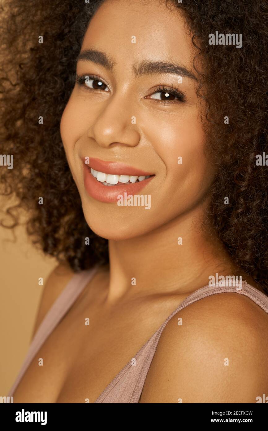 Face closeup of cheerful mixed race young woman with curly hair smiling ...