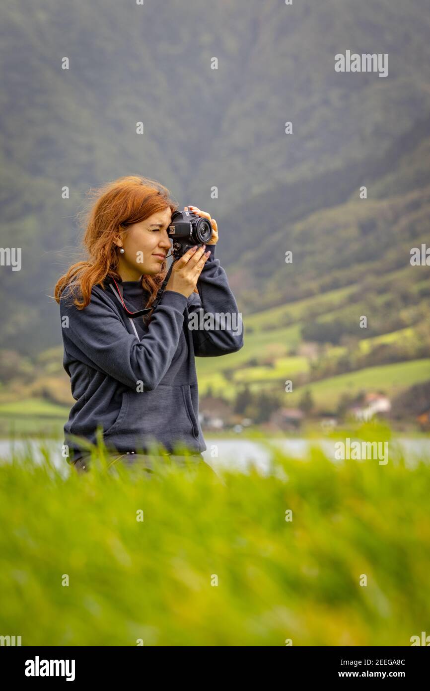 Girl sitting in grass by the lake, Sete Cidades, Sao Miguel island ...