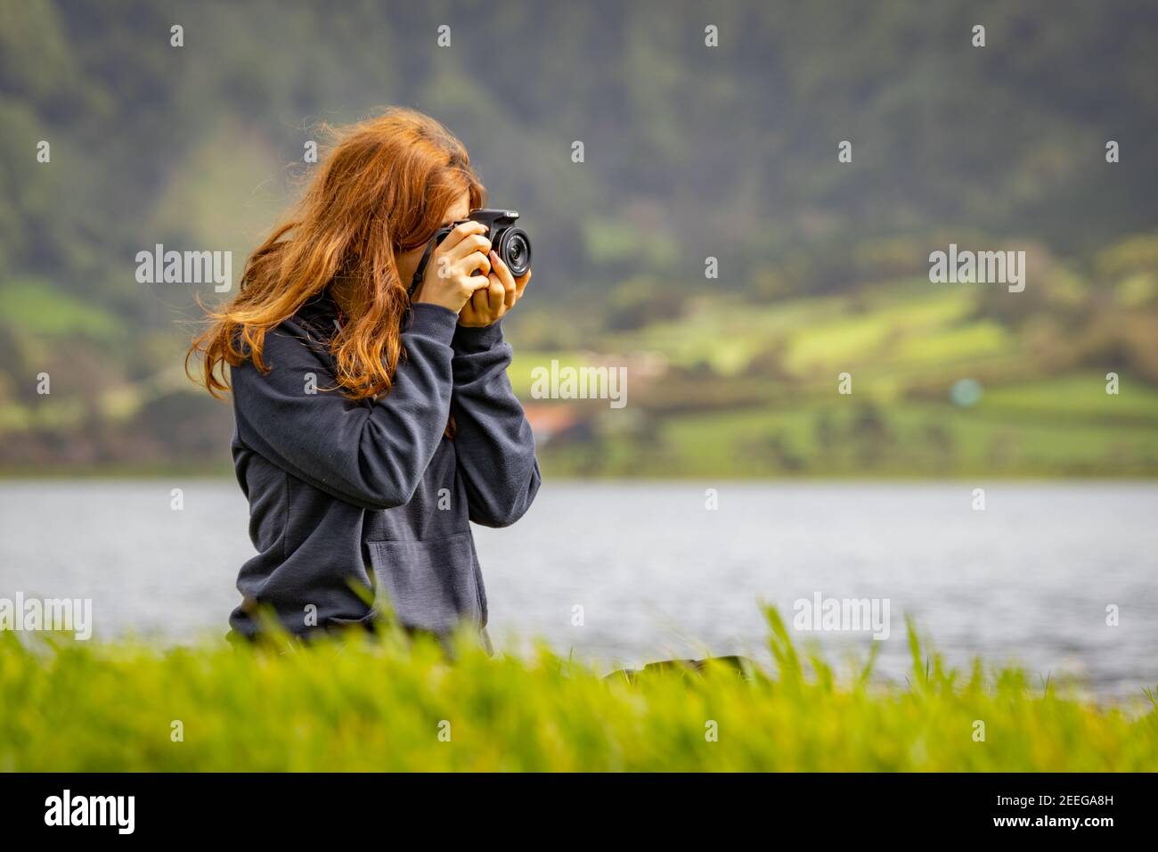 Girl sitting in grass by the lake, Sete Cidades, Sao Miguel island ...