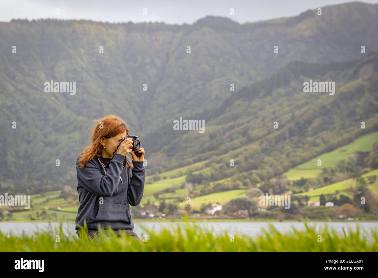 Girl sitting in grass by the lake, Sete Cidades, Sao Miguel island ...