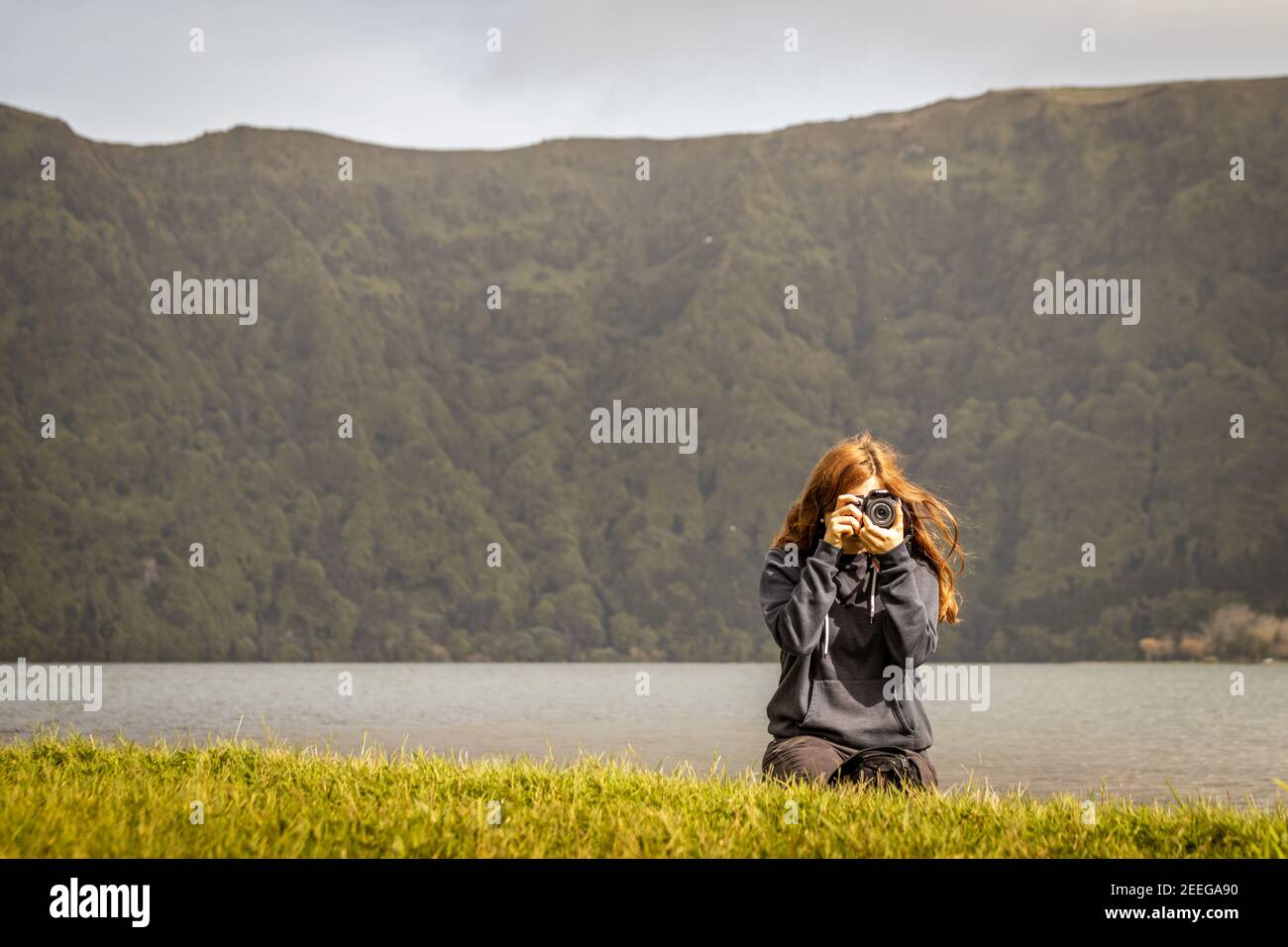 Girl sitting in grass by the lake, Sete Cidades, Sao Miguel island ...
