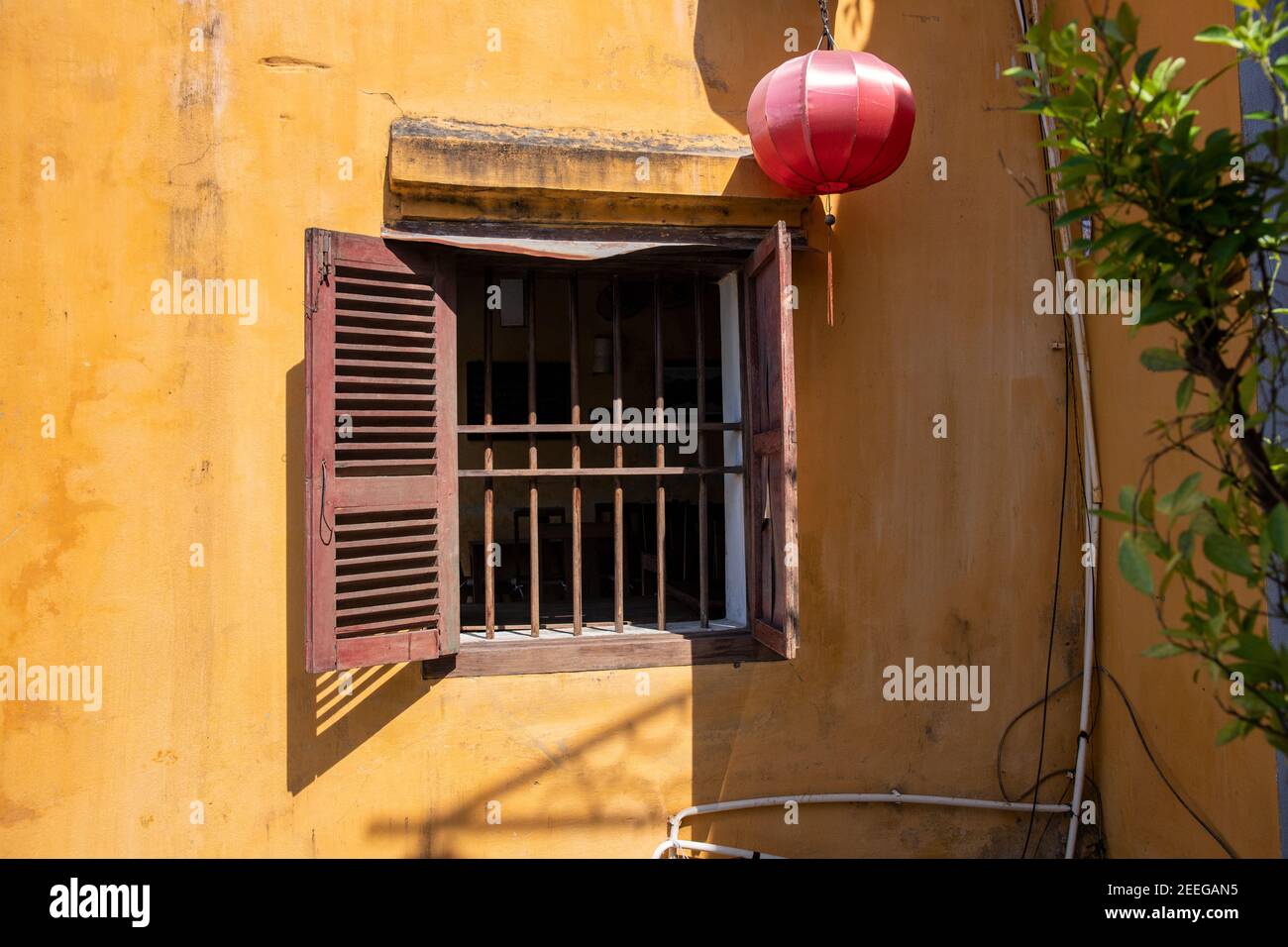 Old house window with shutter, yellow wall and red lantern. Hoi An ...