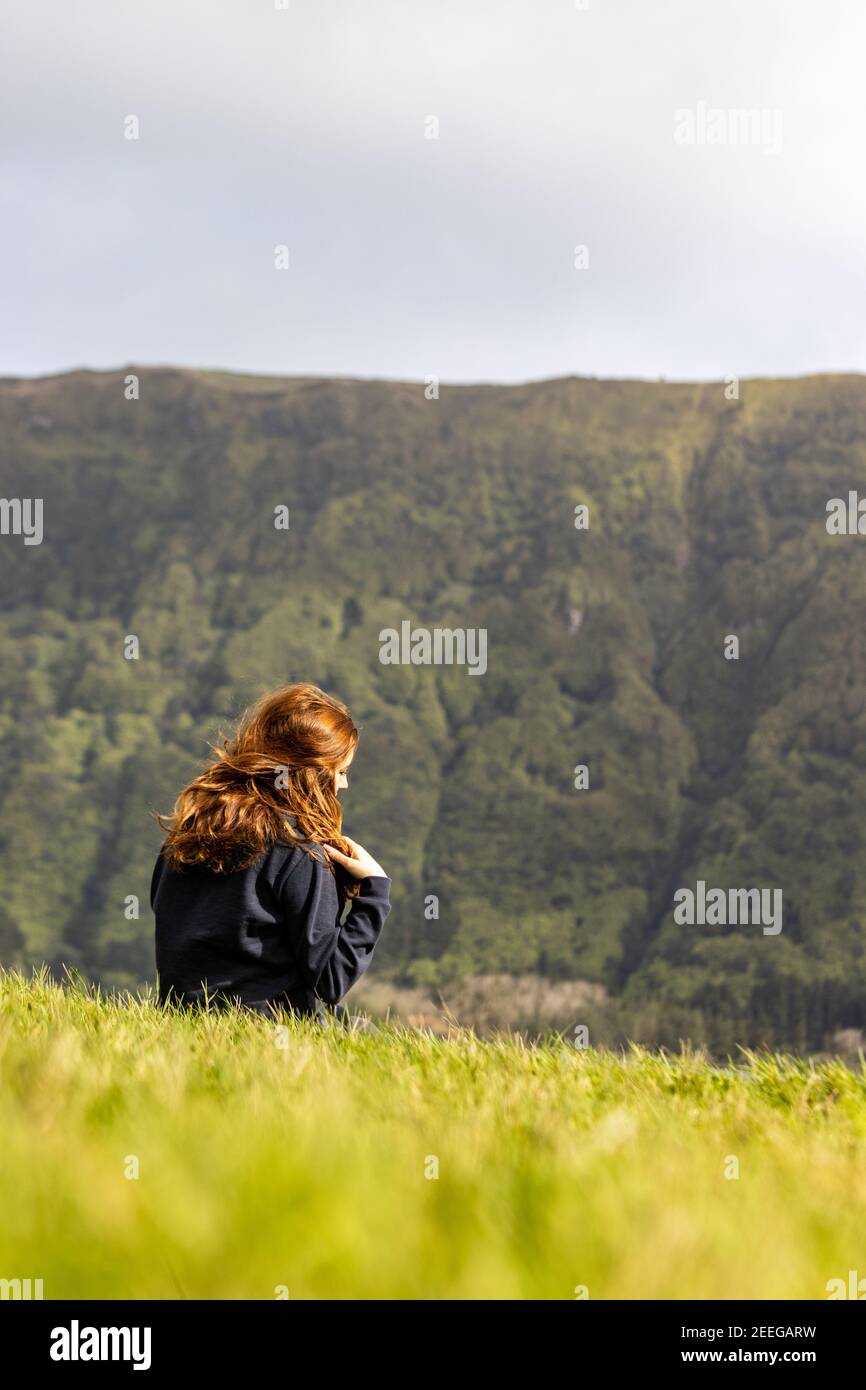 Girl sitting in grass by the lake, Sete Cidades, Sao Miguel island ...