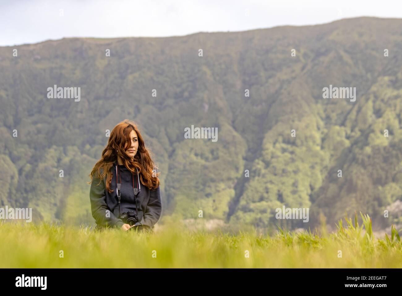 Girl sitting in grass by the lake, Sete Cidades, Sao Miguel island ...