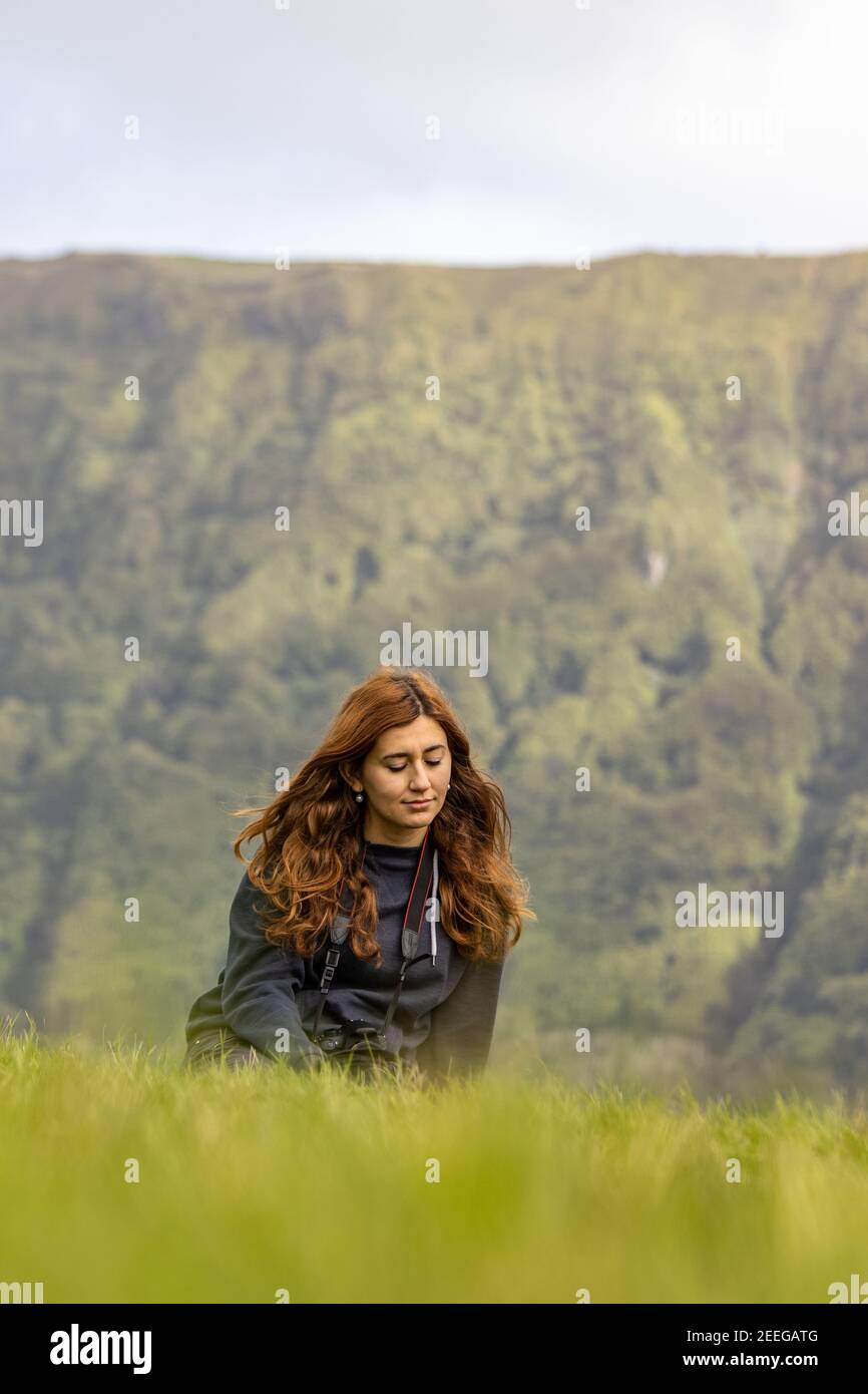 Girl sitting in grass by the lake, Sete Cidades, Sao Miguel island ...