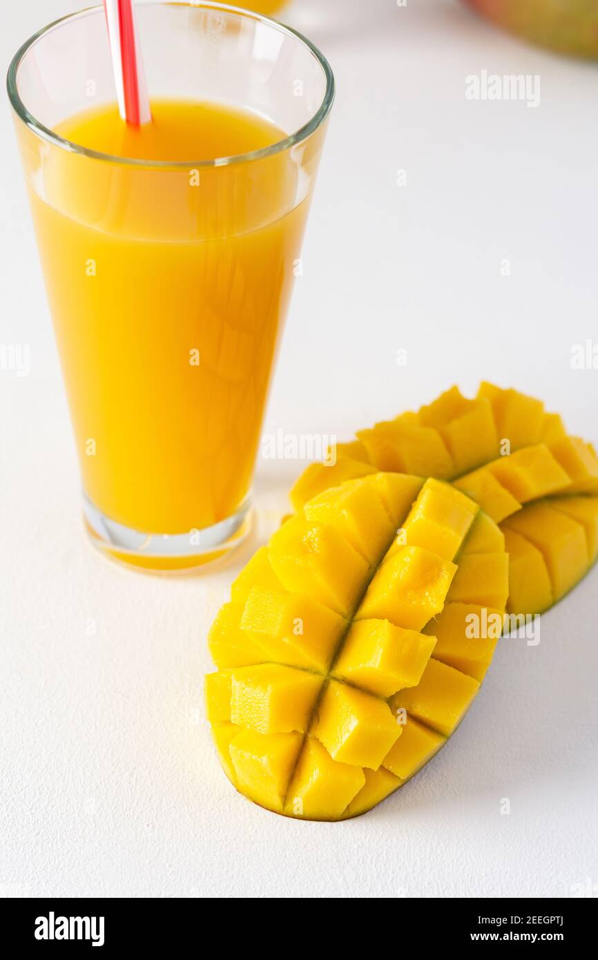 Mango juice in a glass with a straw on a white background, chopped ...
