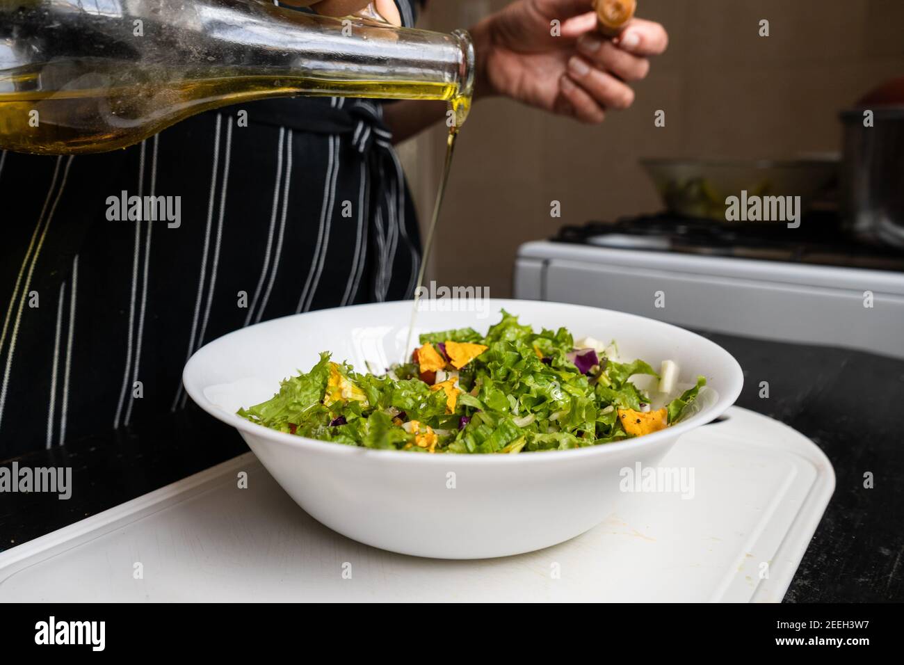 Chef seasoning a vegan salad with olive oil Stock Photo - Alamy