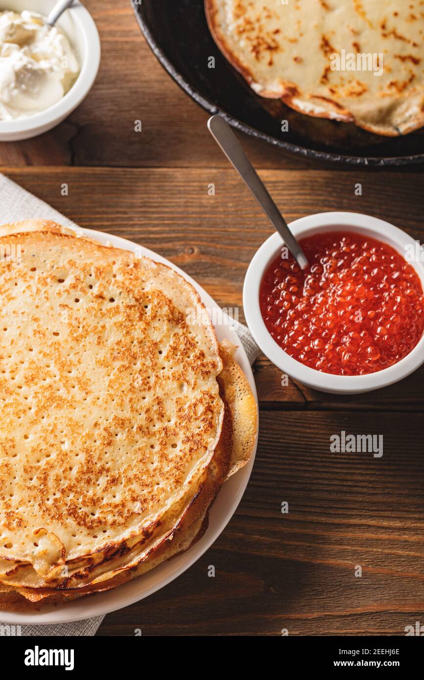 Traditional Russian Crepes Blini stacked in plate and cast-iron frying ...