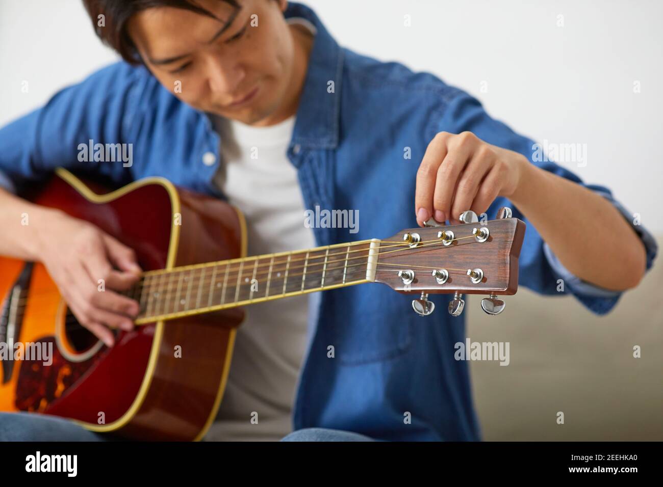 Japanese man playing guitar at home Stock Photo - Alamy