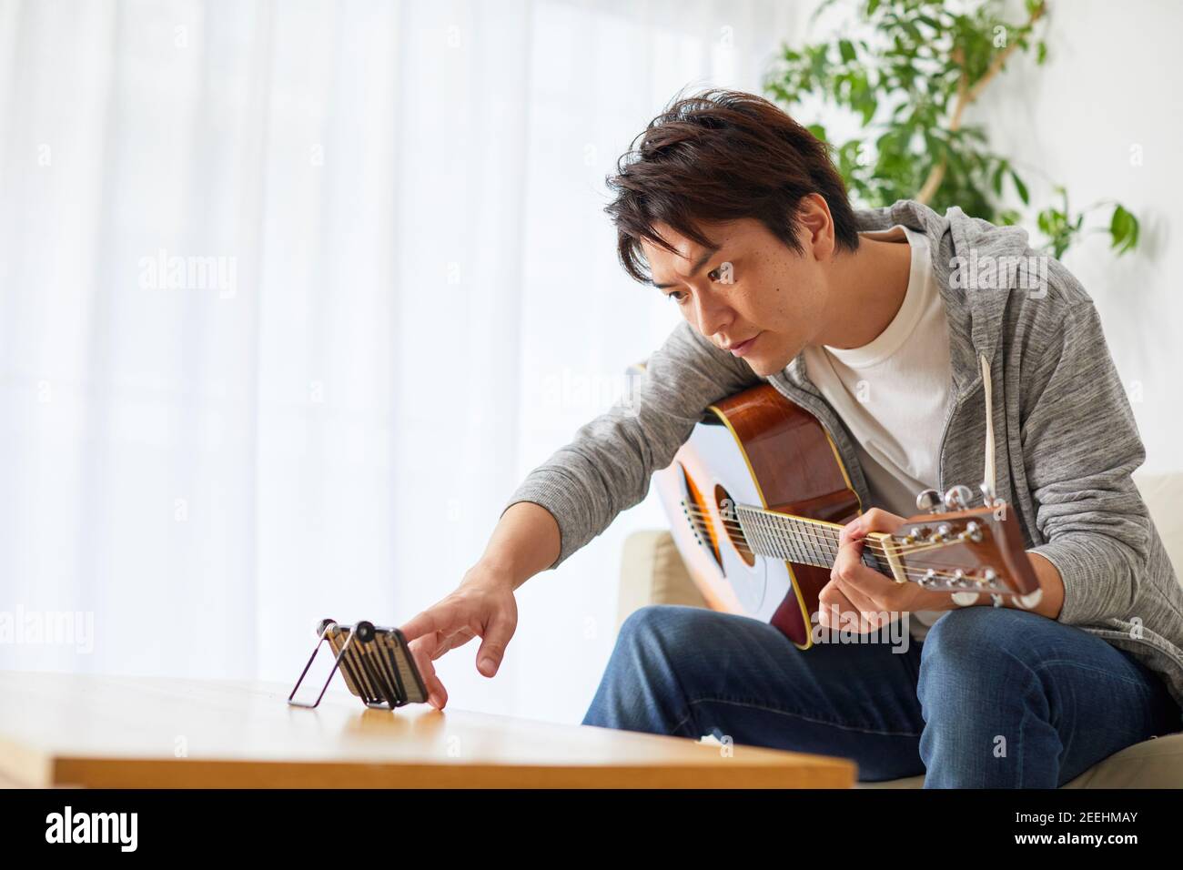 Japanese man playing guitar at home Stock Photo - Alamy