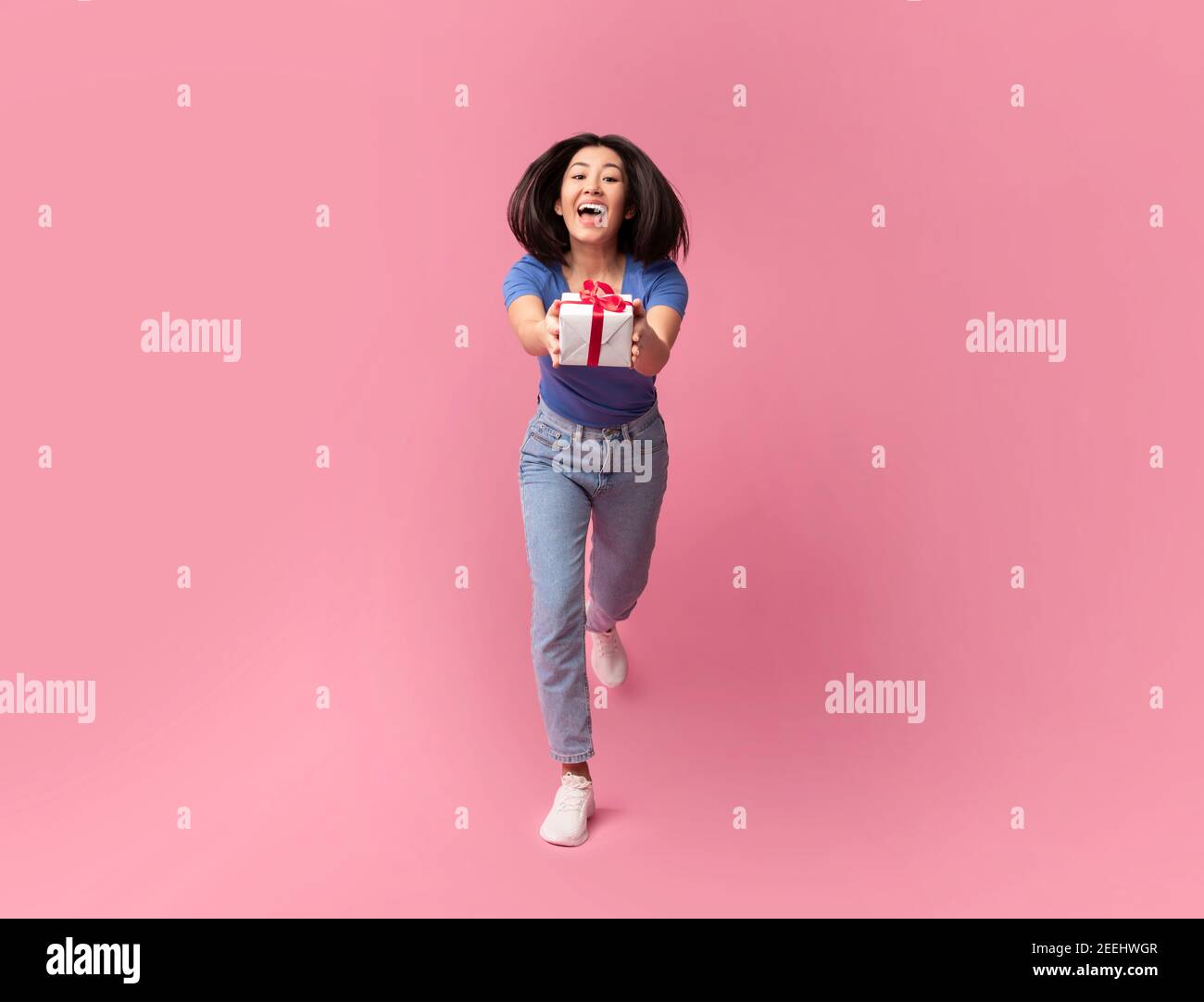 Jumping excited asian lady holding and giving present box Stock Photo ...