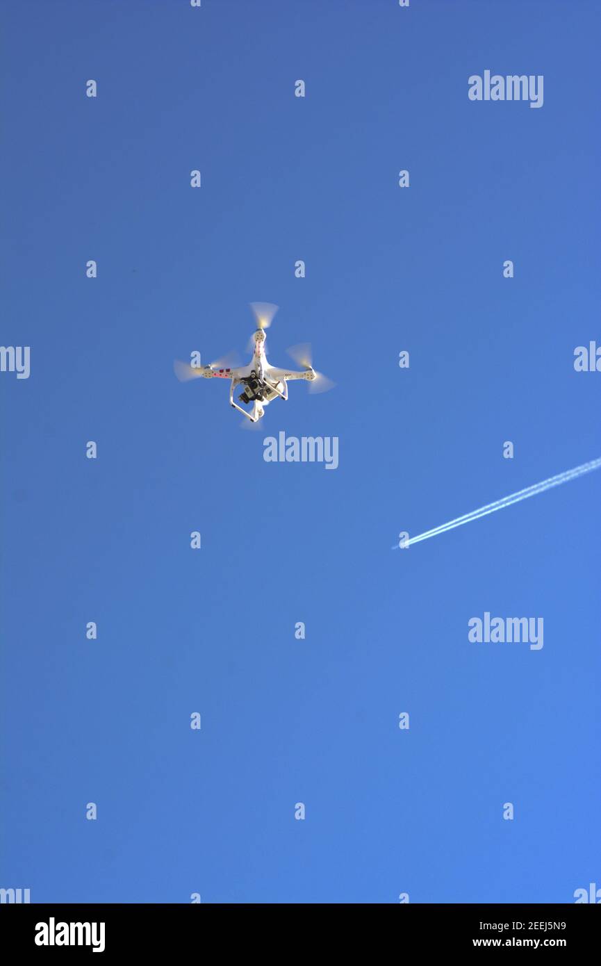 Vertical shot of a drone and plane trails in the blue sky Stock Photo ...