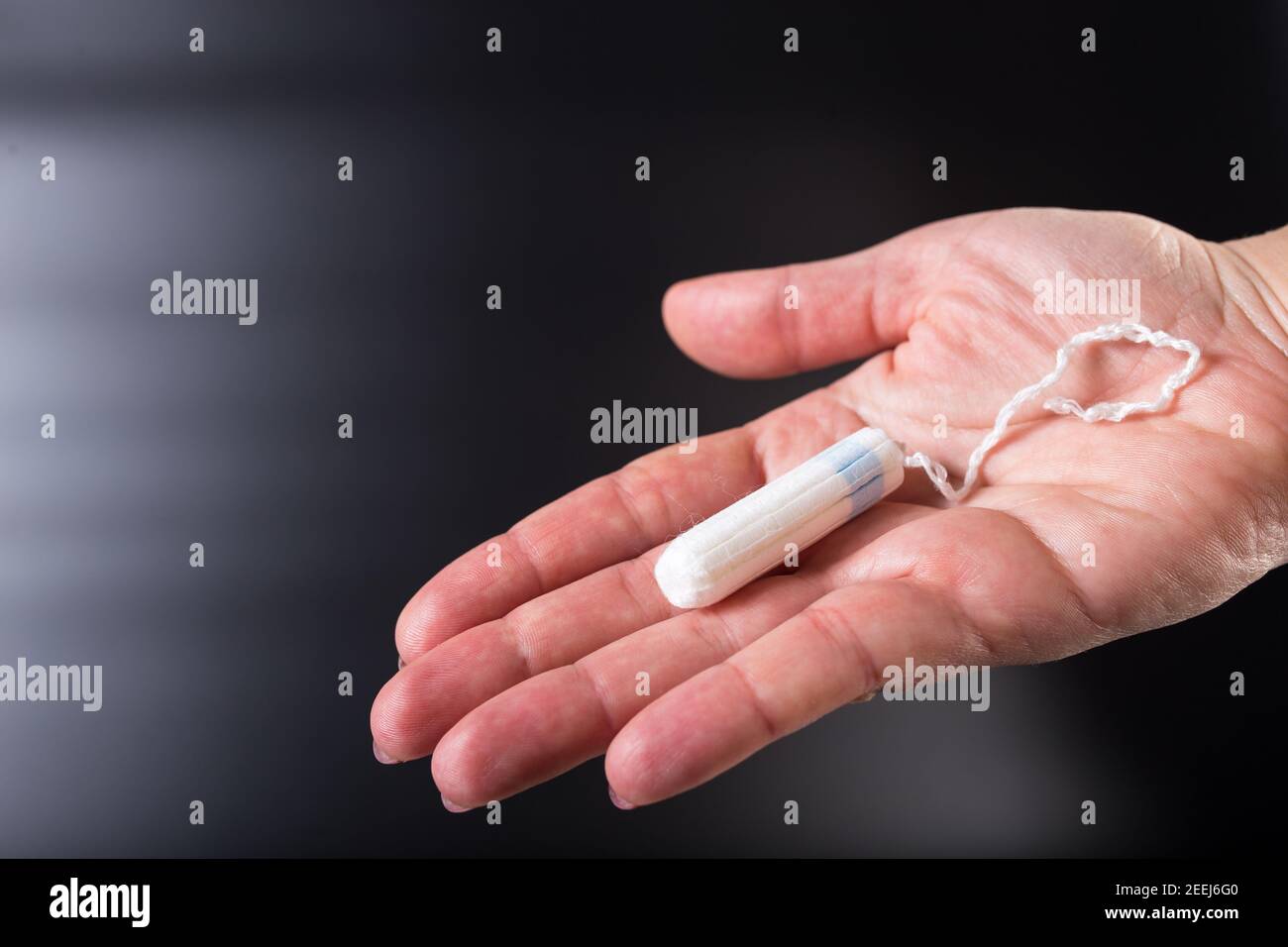 Tampon on woman hand close up, on black background with copy space ...