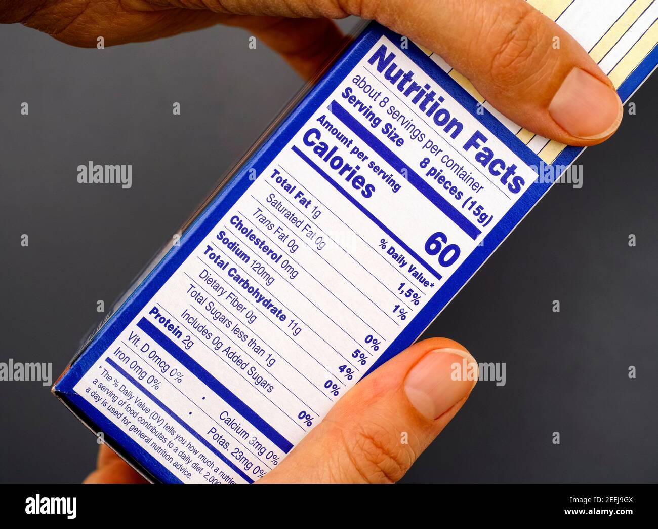 Nutrition facts on food box in person hands. Gray background Stock ...