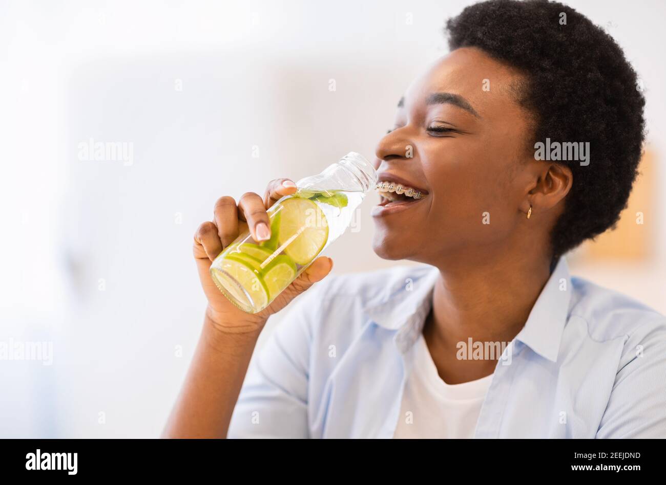 Happy African Woman Drinking Infused Water Posing With Bottle Indoors ...