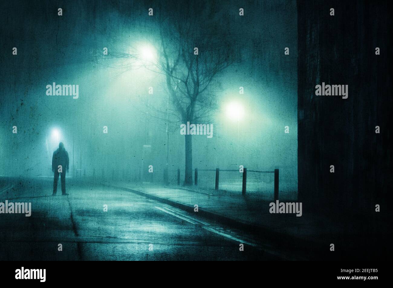 A moody figure. Standing in a street in a city on a foggy winters night ...