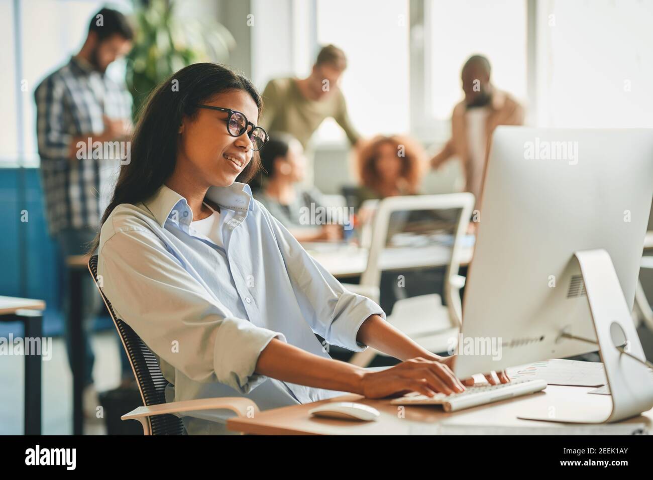 Smiley female office worker using computer at desk Stock Photo - Alamy