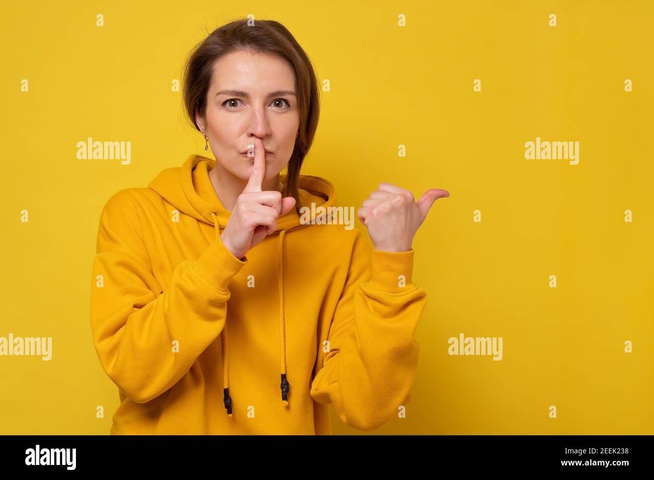 Female student holding finger on lips mouth to keep it quiet secret ...