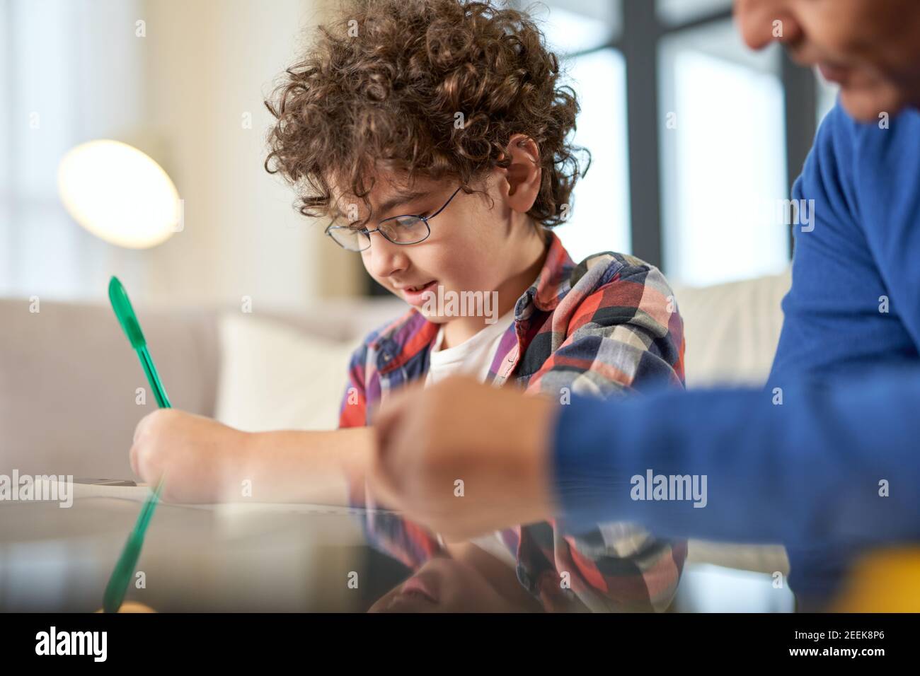 Curious latin school boy looking concentrated, writing on the paper ...