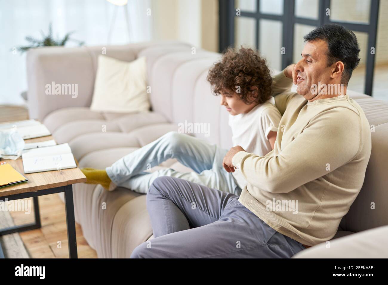 Happy latin middle aged father spending time with his son, watching tv ...