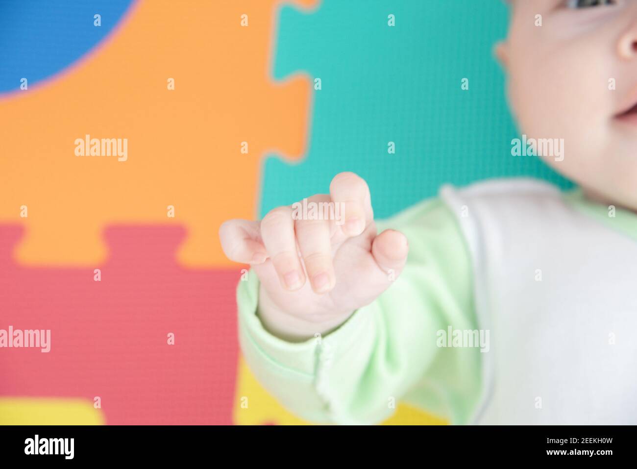 Laughing child on a colored rubber mat puzzle for playing foam eva with ...