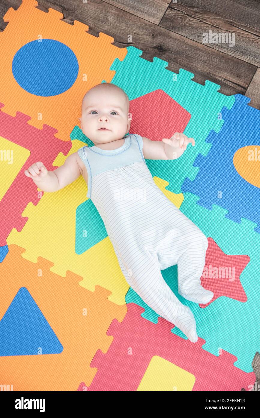 Laughing child on a colored rubber mat puzzle for playing foam eva with ...