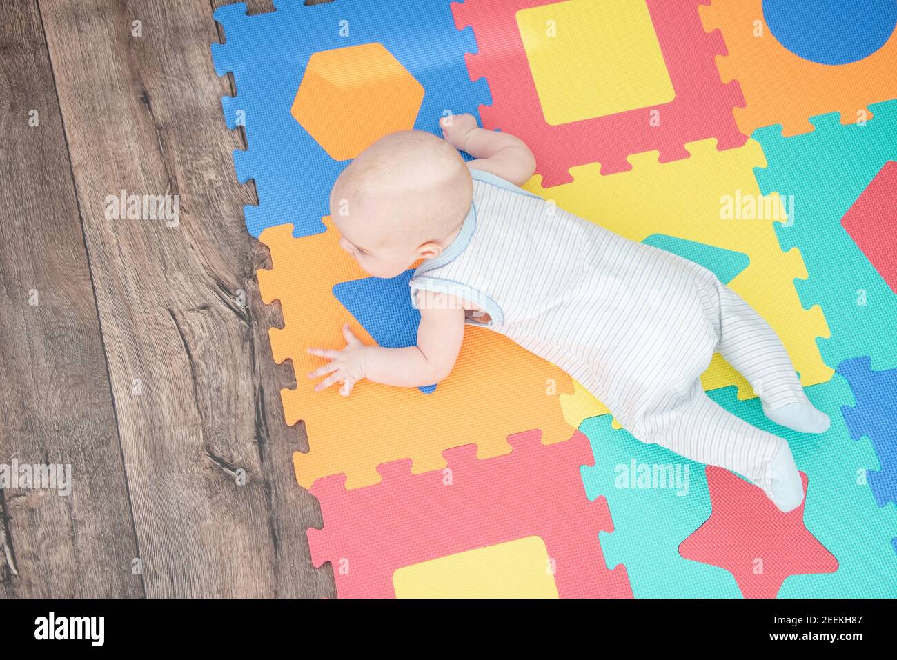 Laughing child on a colored rubber mat puzzle for playing foam eva with ...