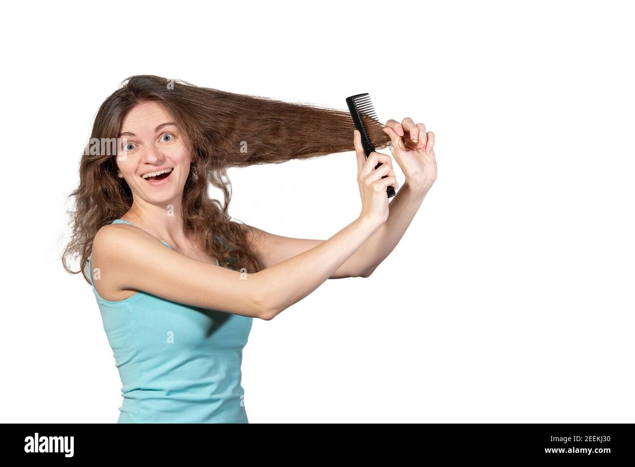Beautiful brunette girl combing curly long hair with a comb and smiling ...