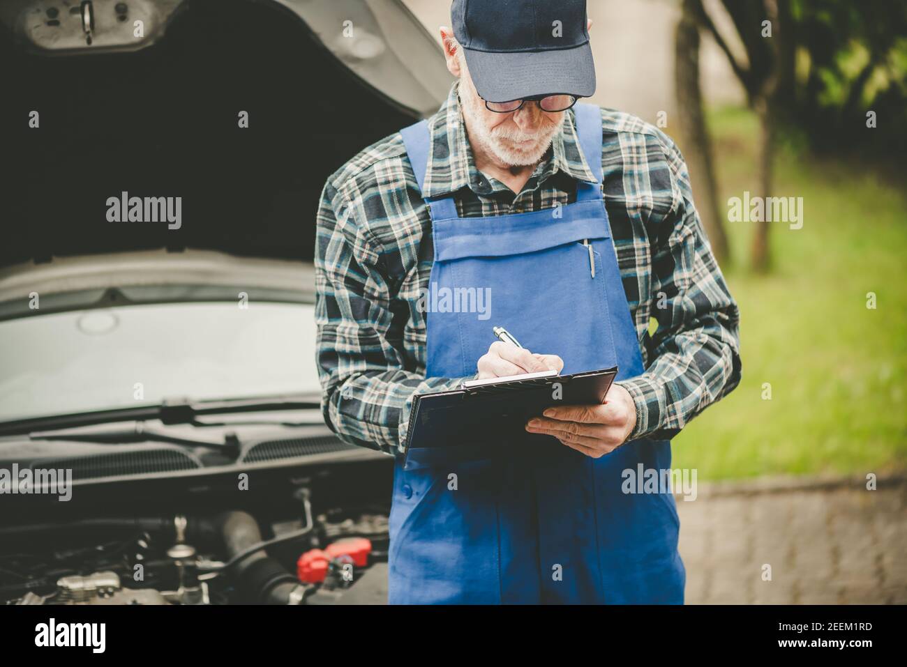 Car mechanic checking a car engine and writing on clipboard Stock Photo ...