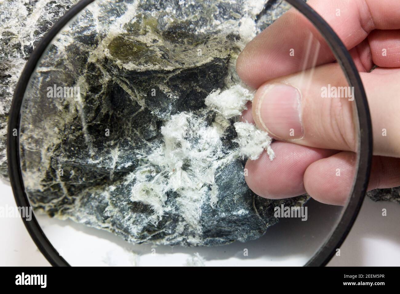 Hand with magnifying glass examines asbestos fibers in stone Stock ...