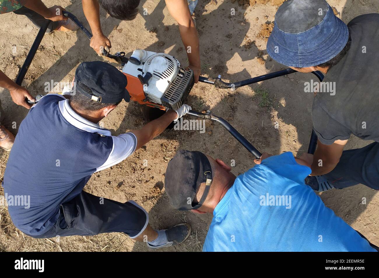 Workers are drilling pits for poles, starting work with a hand drill ...
