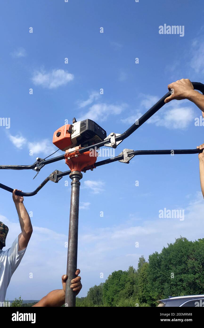 Workers are drilling pits for poles, starting work with a hand drill ...