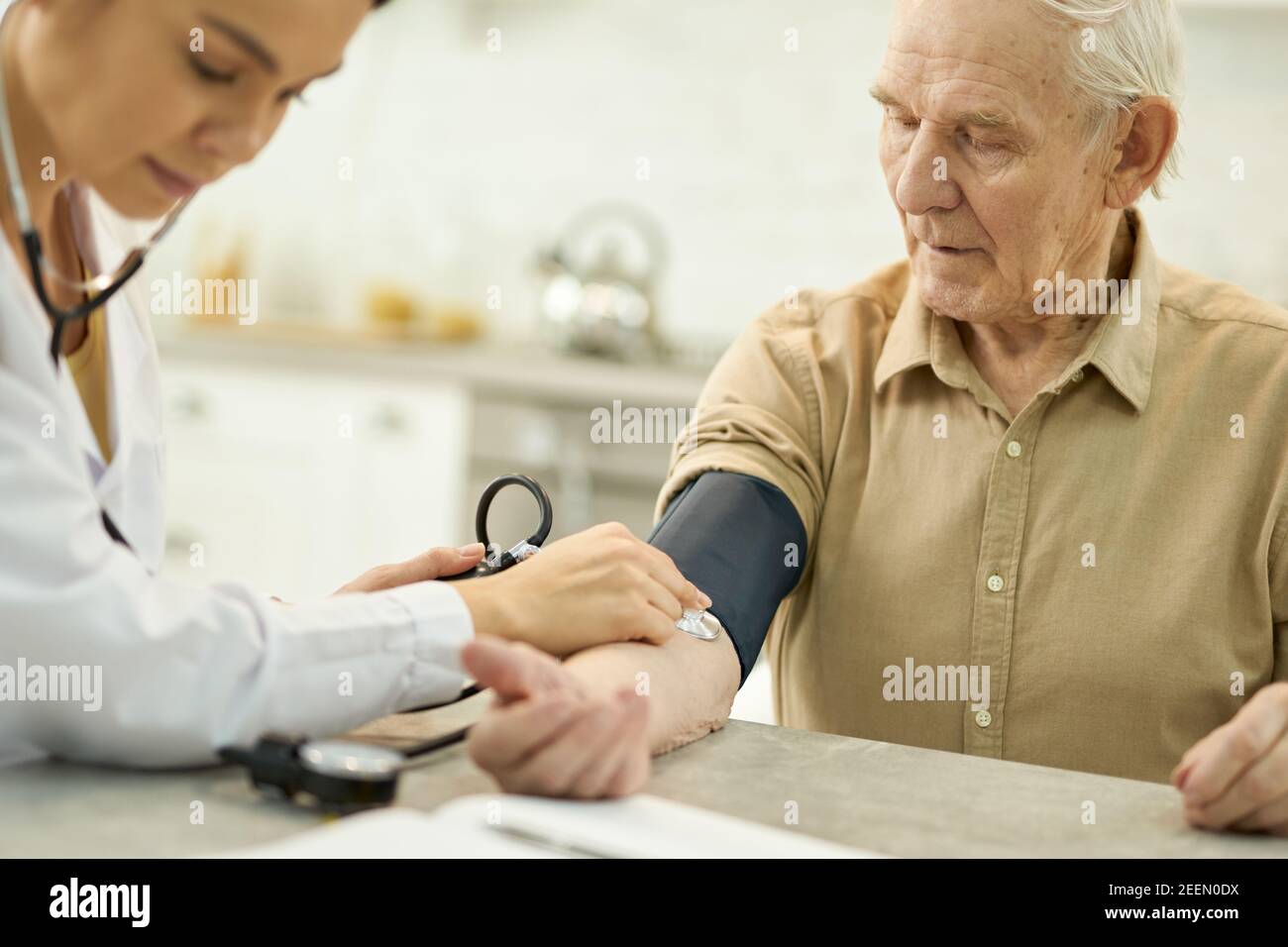 Elderly man with manometer cuff around his upper arm being examined by ...