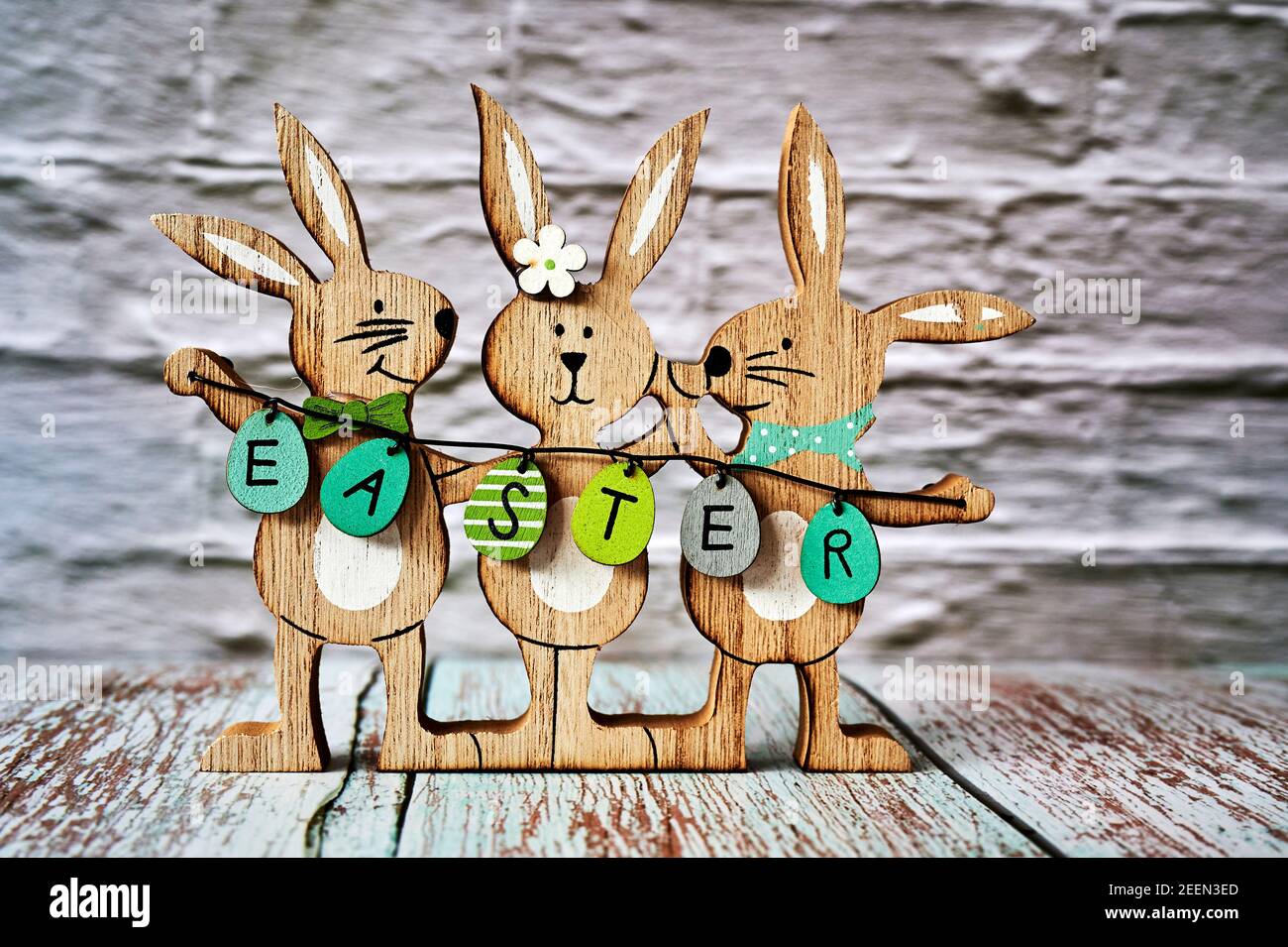 Three wooden Easter bunnies with decoration and the text Easter written ...