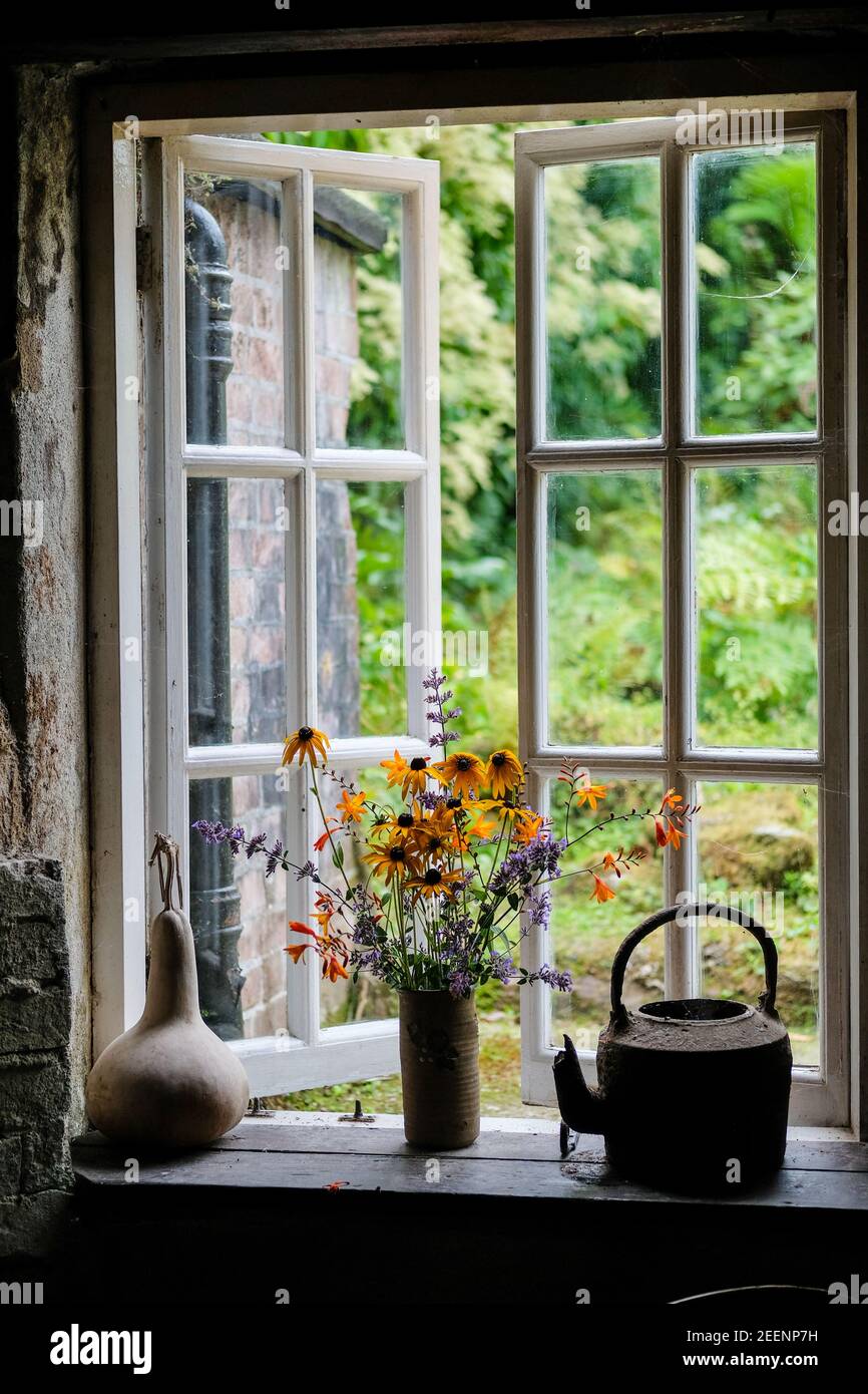 Flower display by an open window in a traditional English cottage Stock ...