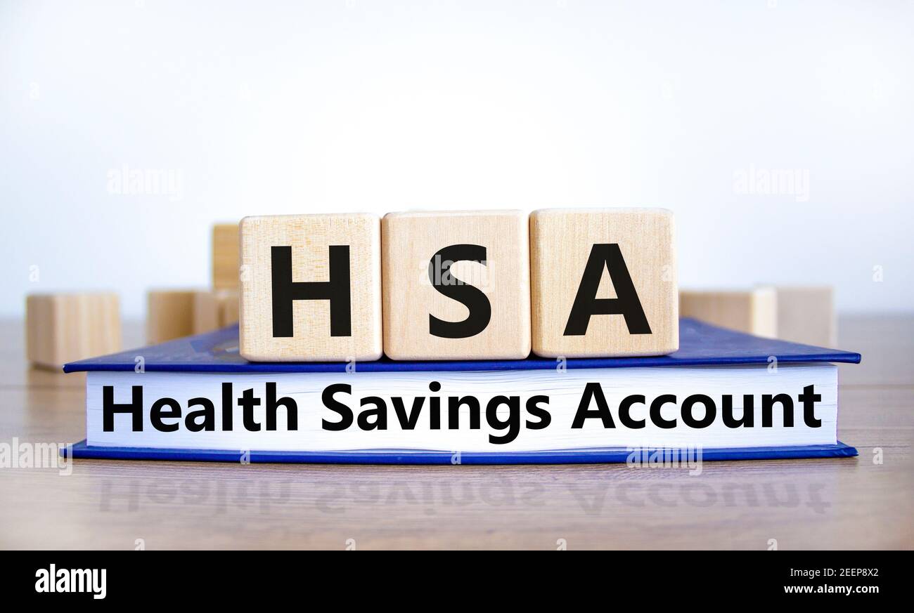 HSA, health savings account symbol. Wooden cubes on book with words ...