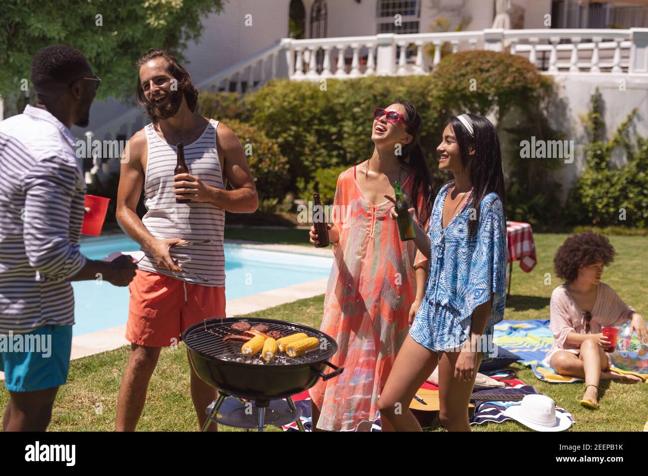 Diverse group of friends having barbecue and talking at a pool party ...