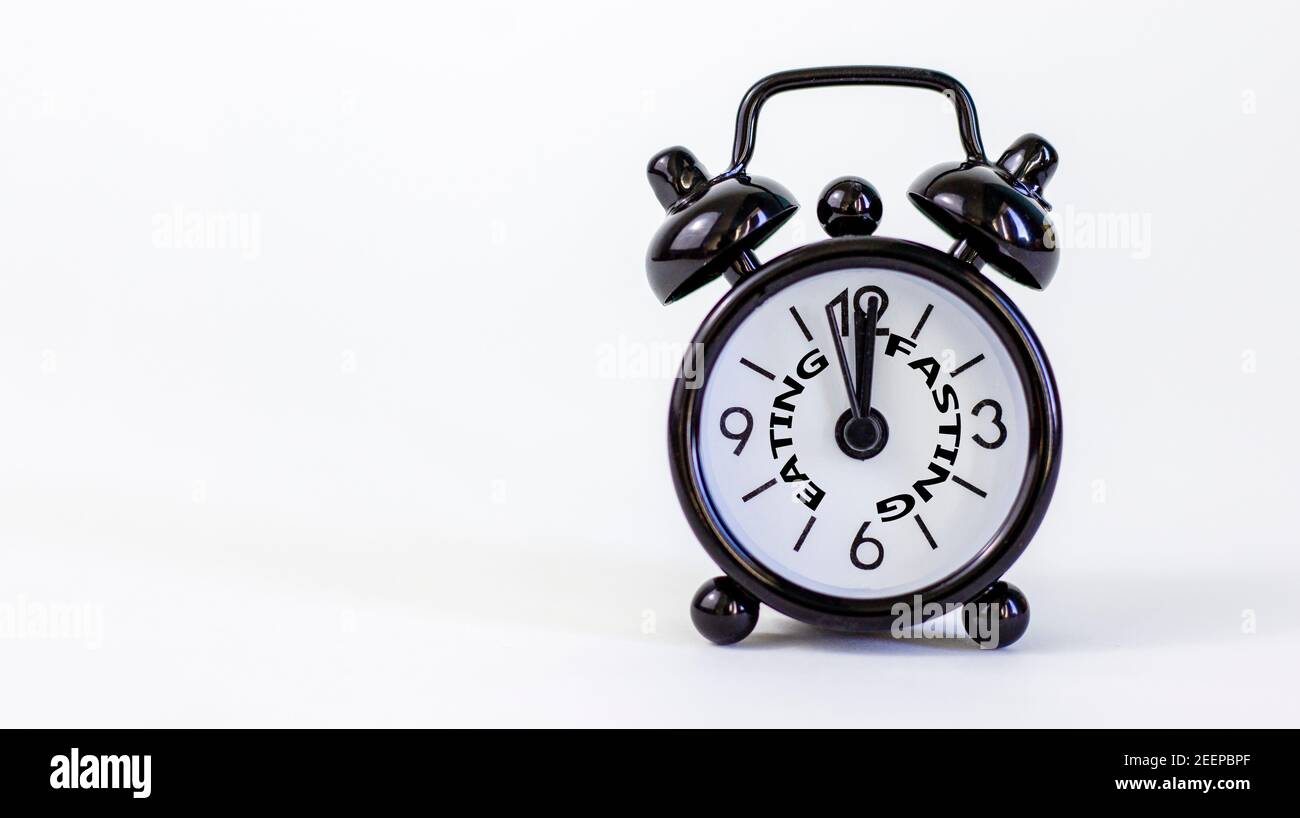 Time to fasting symbol. Beautiful black alarm clock with words 'eating ...