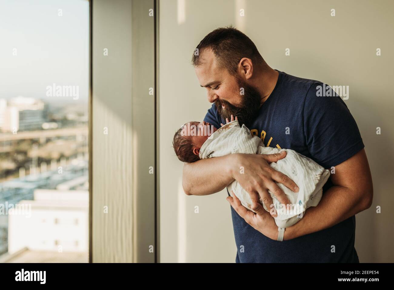 Lifestyle portrait of dad holding newborn baby boy in birthing center ...